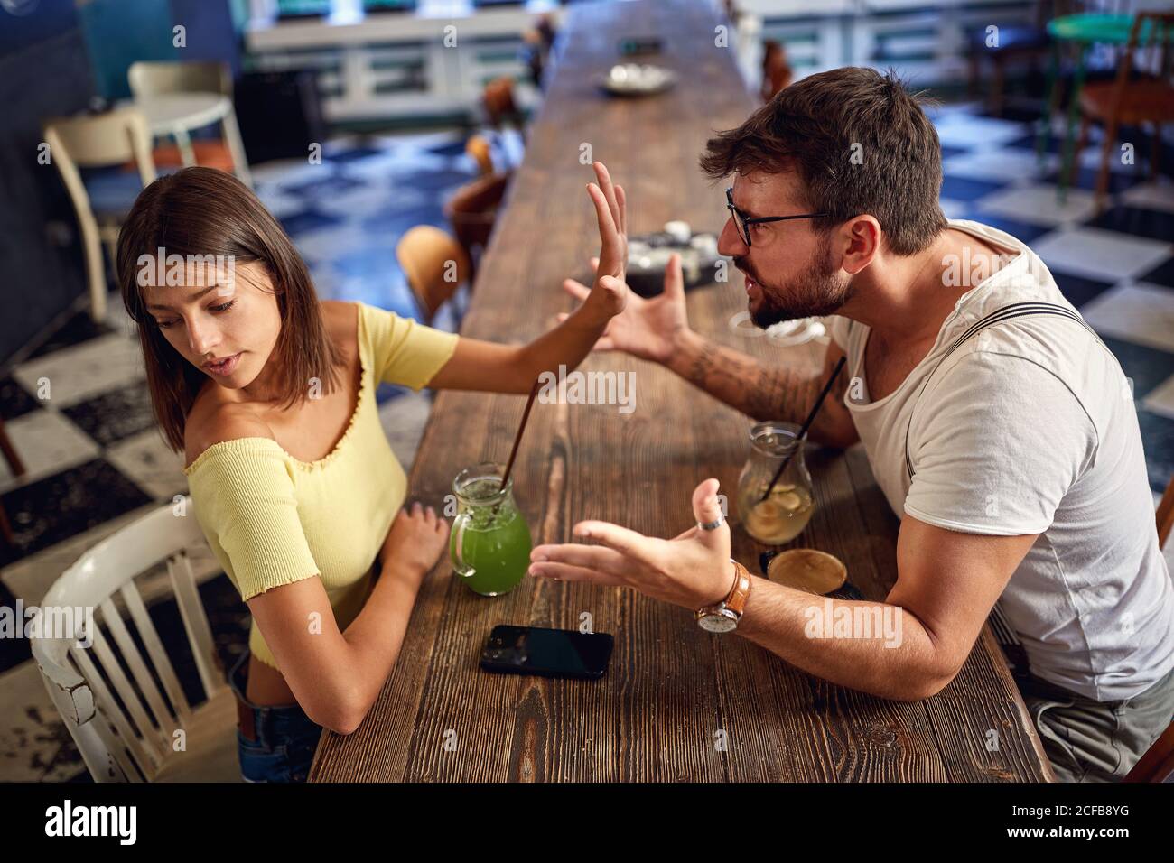 Young couple talking and arguing in a cafe Stock Photo - Alamy
