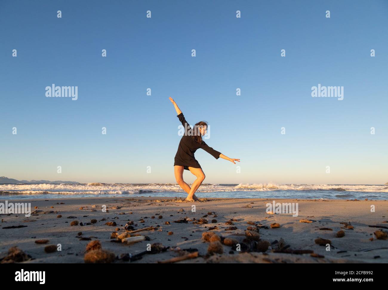 Young dancer posing on sand coast with waving sea and blue sky Stock ...