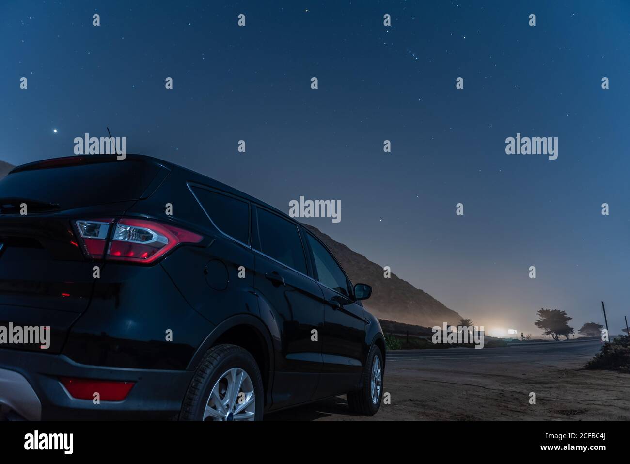 Black compact car parked along highway as constellation Orion is ...