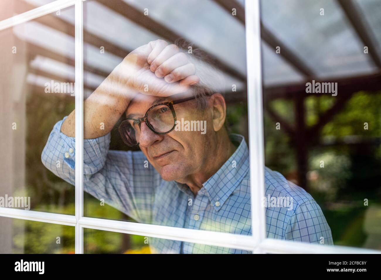 Senior man looking out of window at home Stock Photo - Alamy