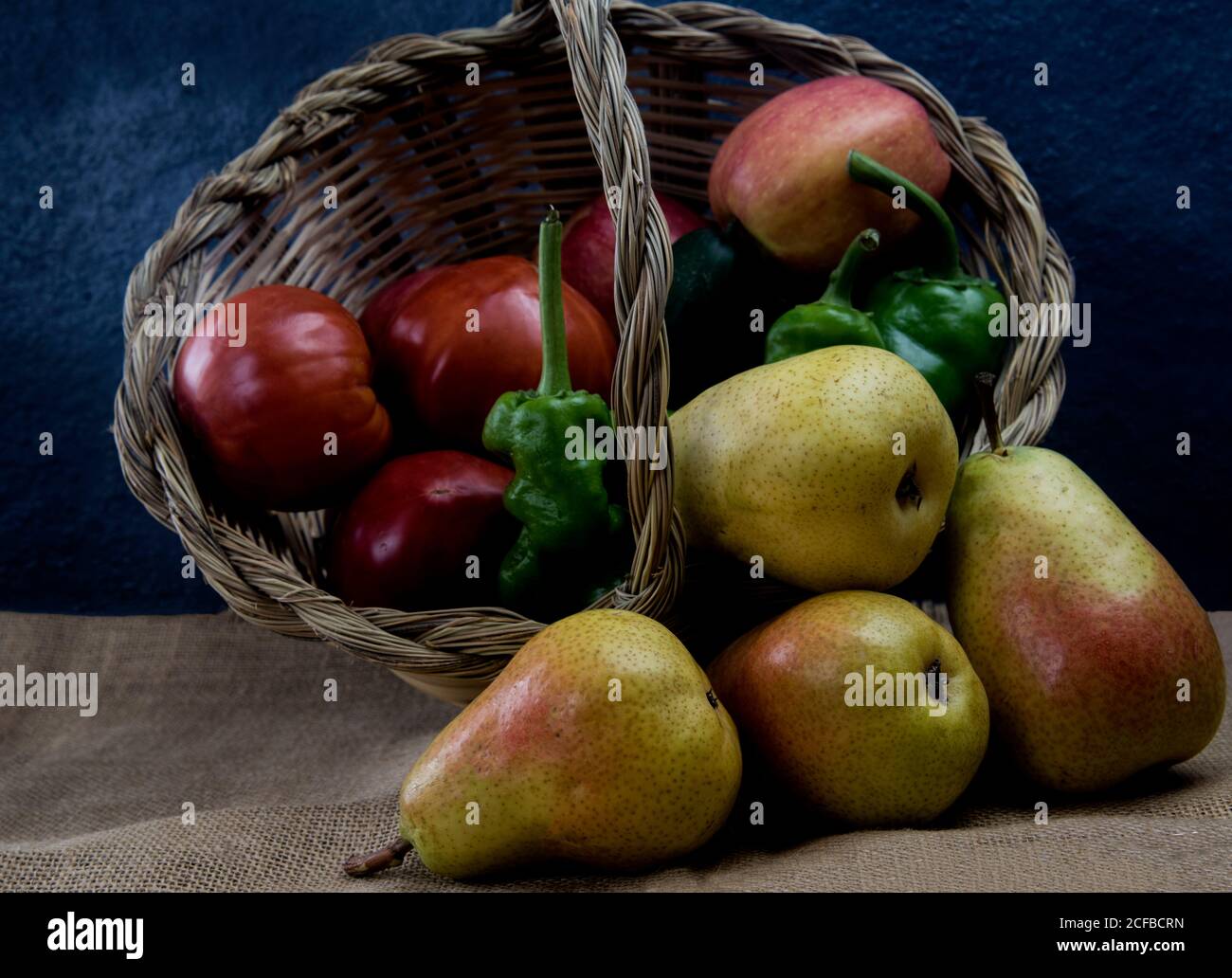 organic fruits and vegetables on a cane basket on rustic bacground ...