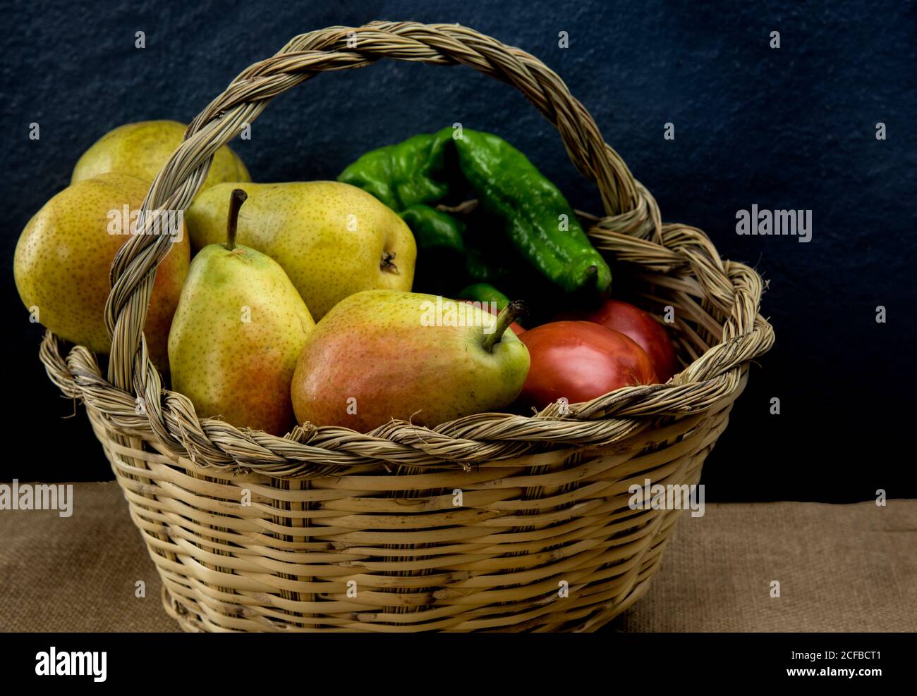 organic fruits and vegetables on a cane basket on rustic bacground ...