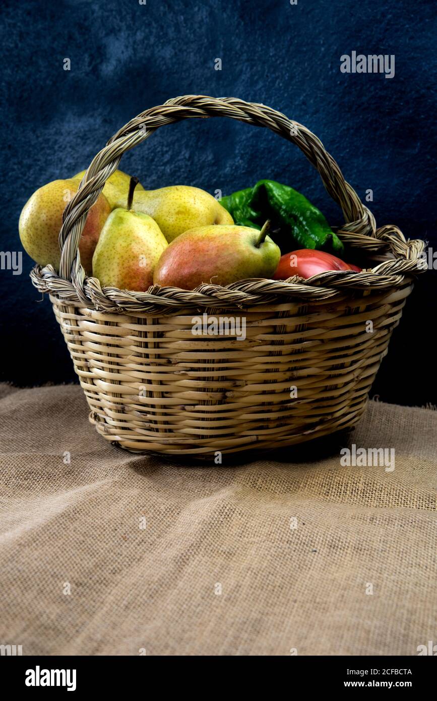 organic fruits and vegetables on a cane basket on rustic bacground ...