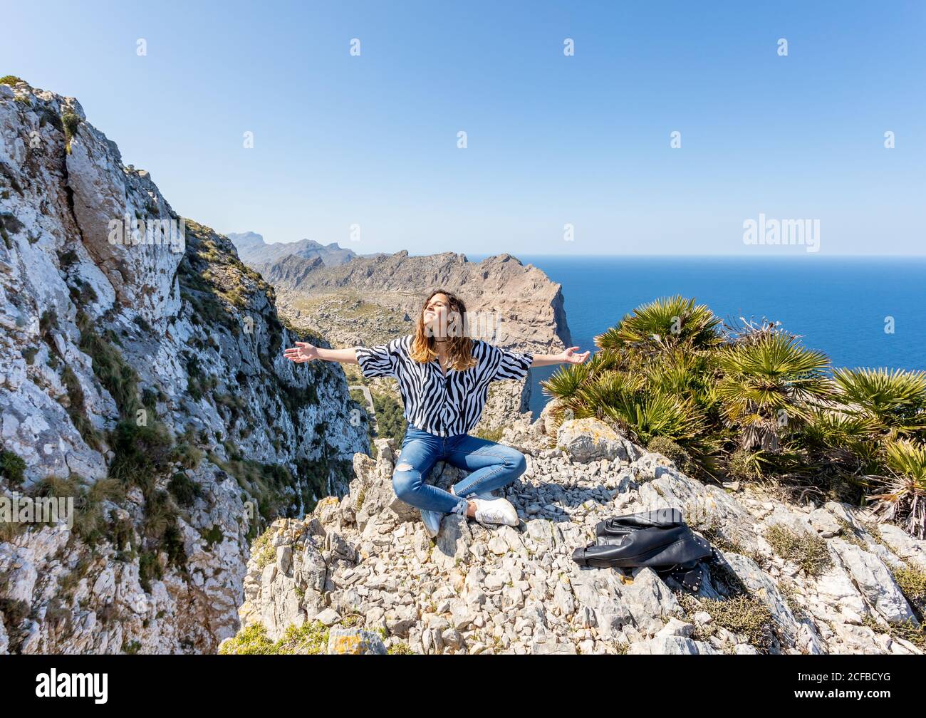 Young Woman sitting on cliff Stock Photo - Alamy