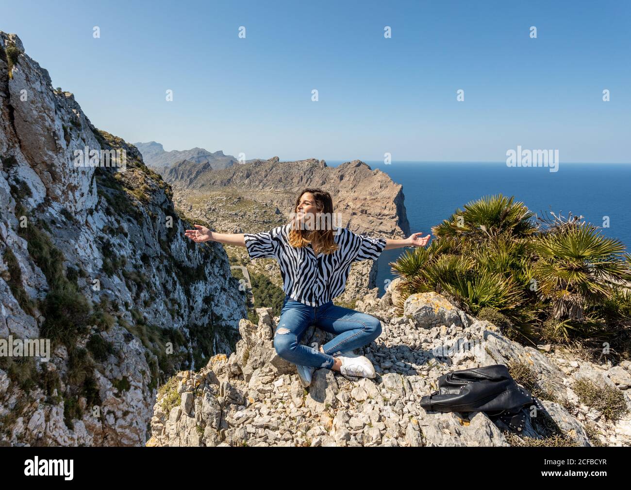 Young Woman sitting on cliff Stock Photo - Alamy