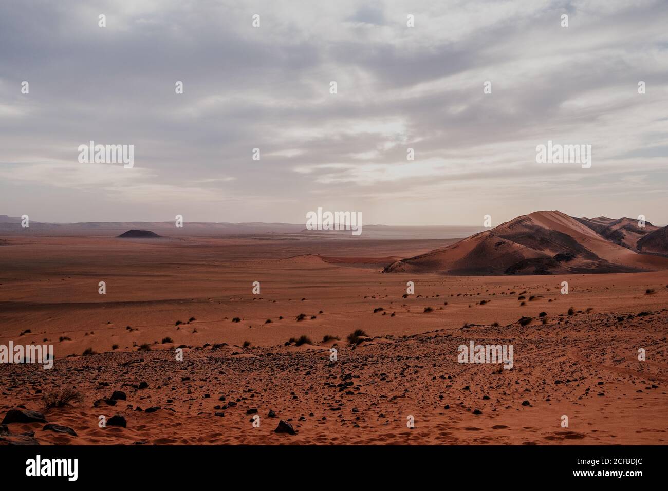Cloudy sundown sky over hills and rocks in arid desert in evening in ...