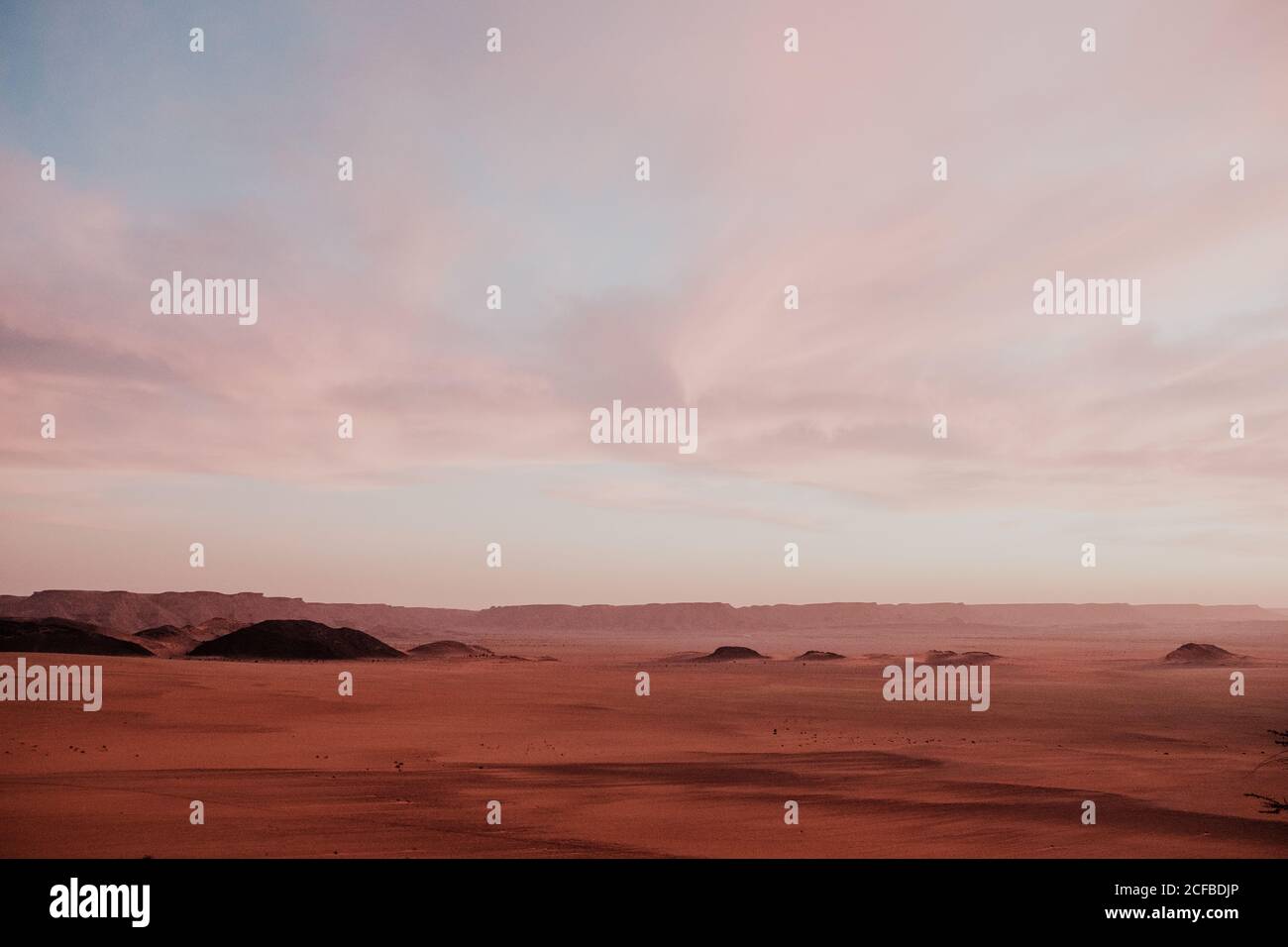 Cloudy sundown sky over hills and rocks in arid desert in evening in ...