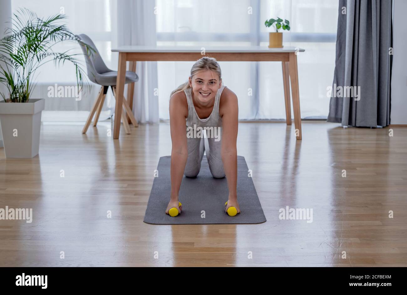 Beautiful active young woman exercise half plank pose with dumbbells at ...