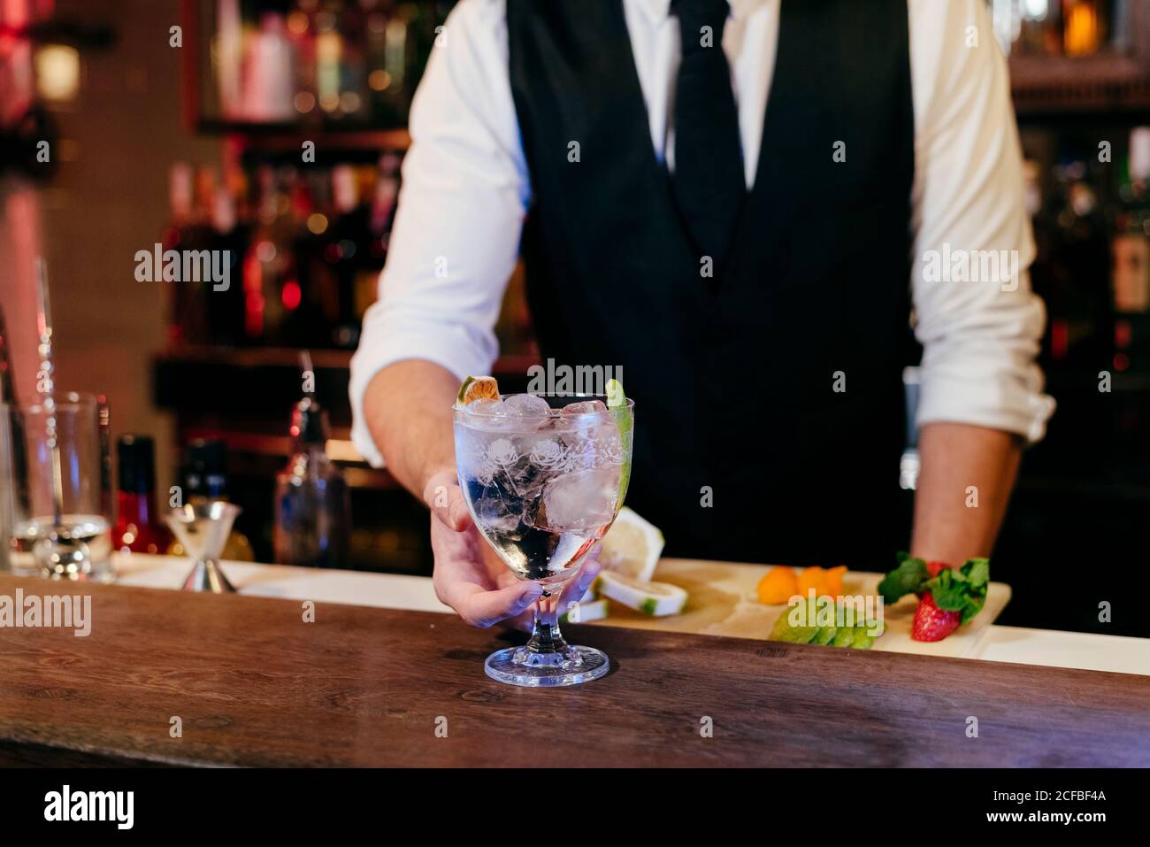 Crop anonymous young elegant barman working behind a bar counter mixing ...