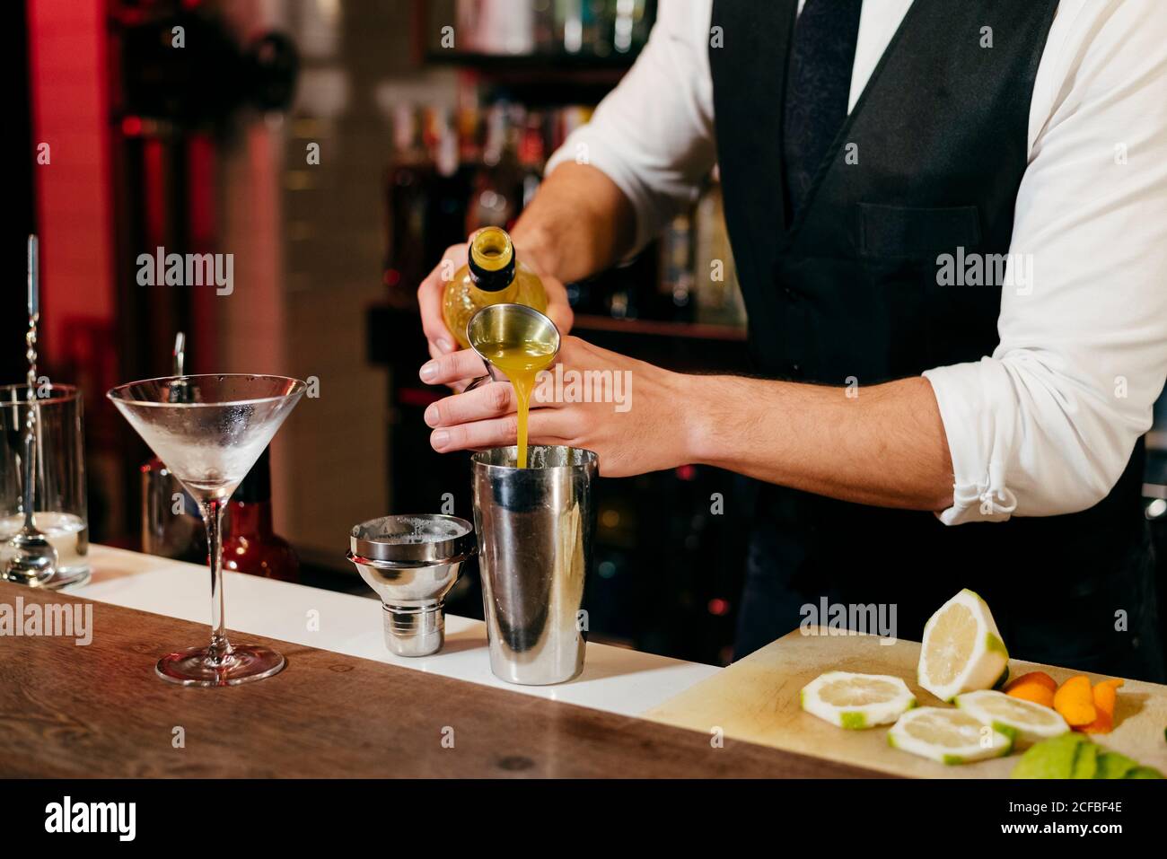 Crop anonymous young elegant barman working behind a bar counter mixing ...