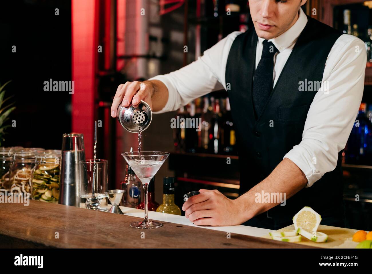 Crop anonymous young elegant barman working behind a bar counter mixing ...
