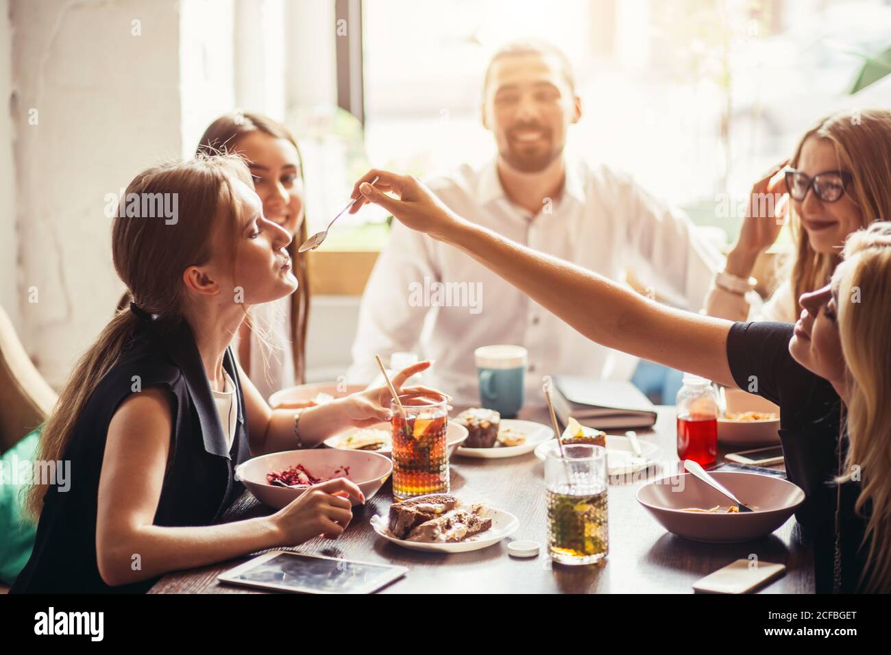 glamourous young woman laughing, feeding ice-cream to her friend Stock ...