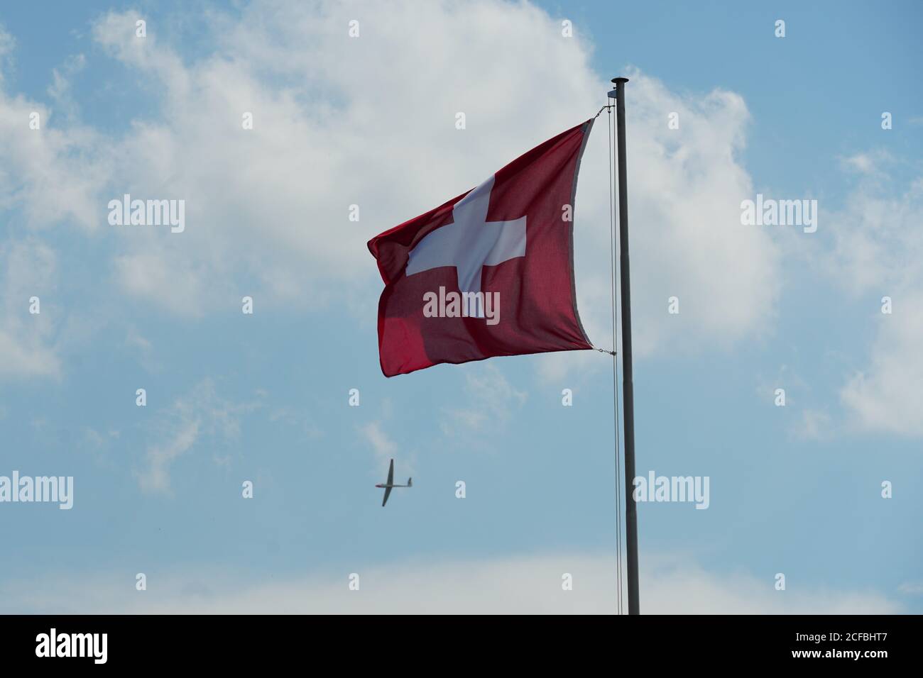 Flapping flag of Switzerland displays a white cross in the centre of a ...