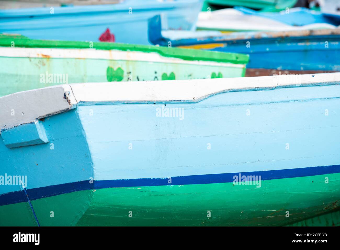 Blue and Green boats sit on the shore Stock Photo - Alamy