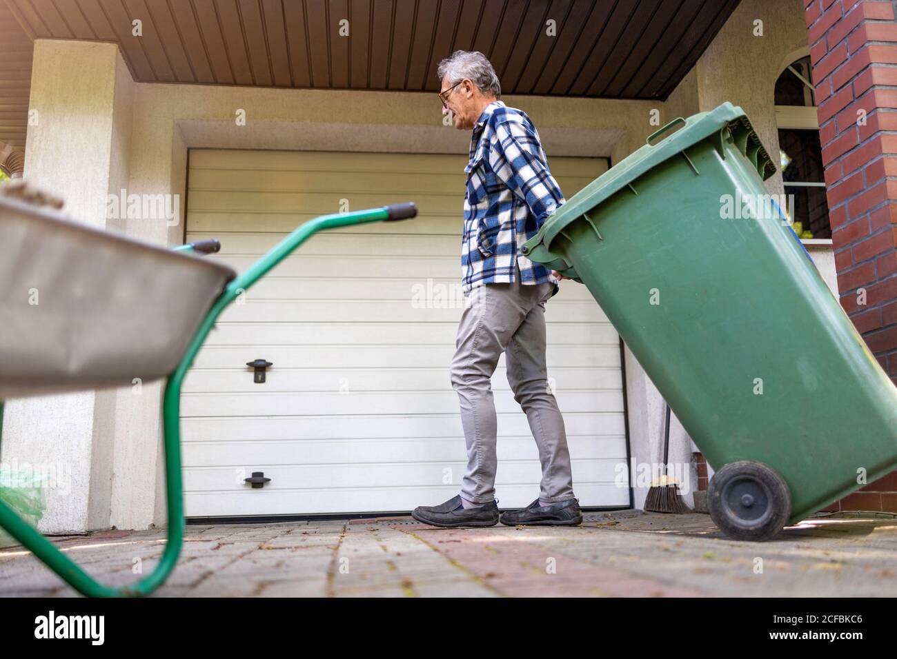 Senior man taking out garbage Stock Photo - Alamy