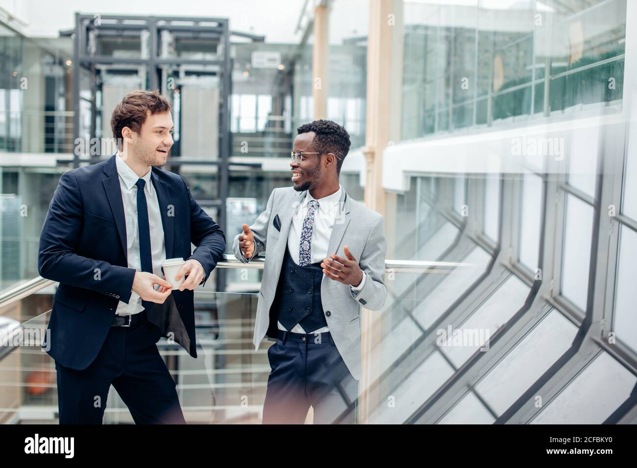 Two multiethnic male employees consulting in office Stock Photo - Alamy