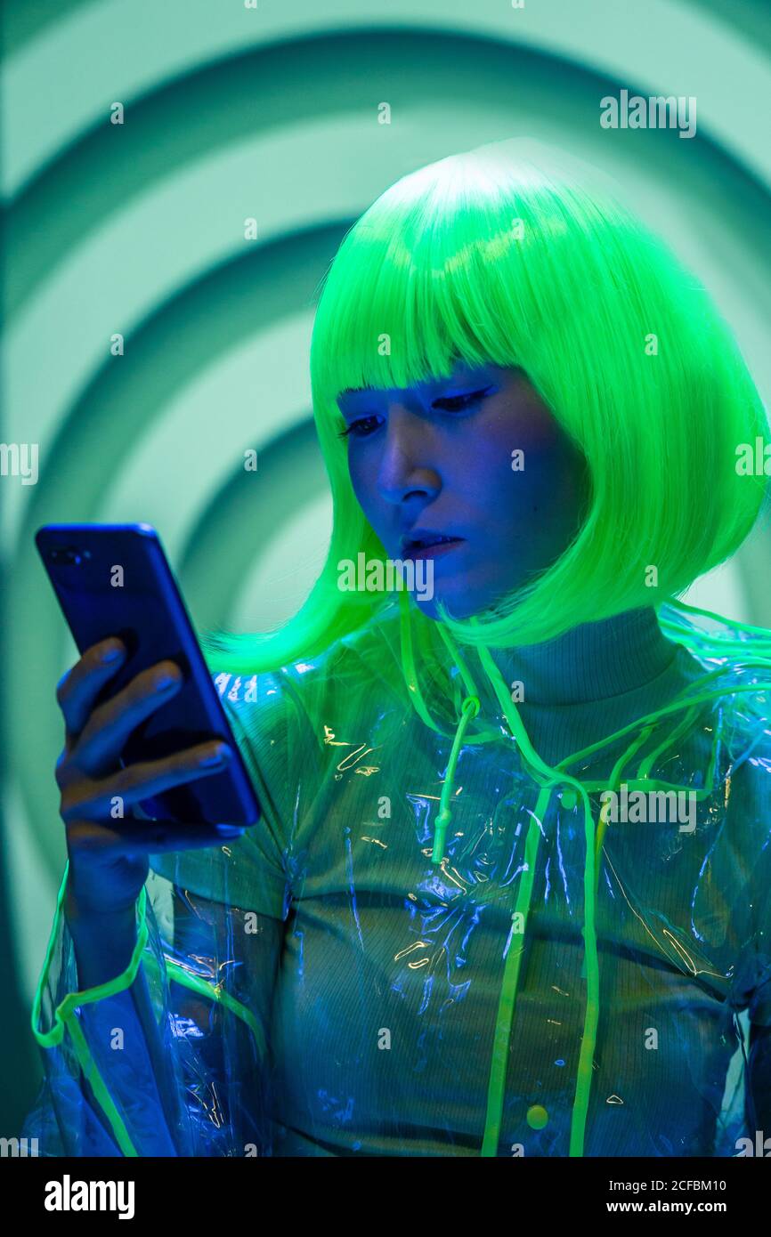 Young asian Woman in futuristic wear and green wig using smartphone in ...
