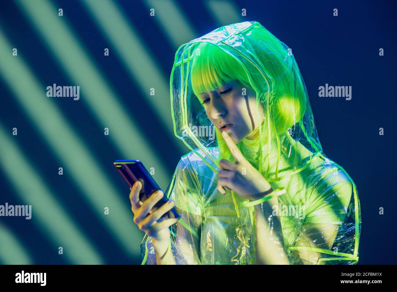 Young asian Woman in futuristic wear and green wig using smartphone in ...