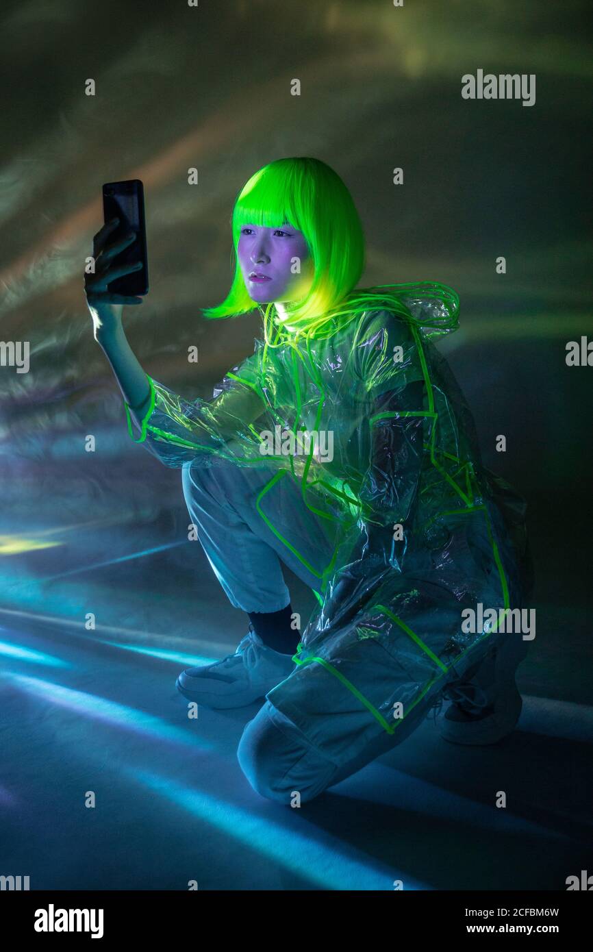 Young Asian Woman in futuristic wear and green wig taking selfie on ...