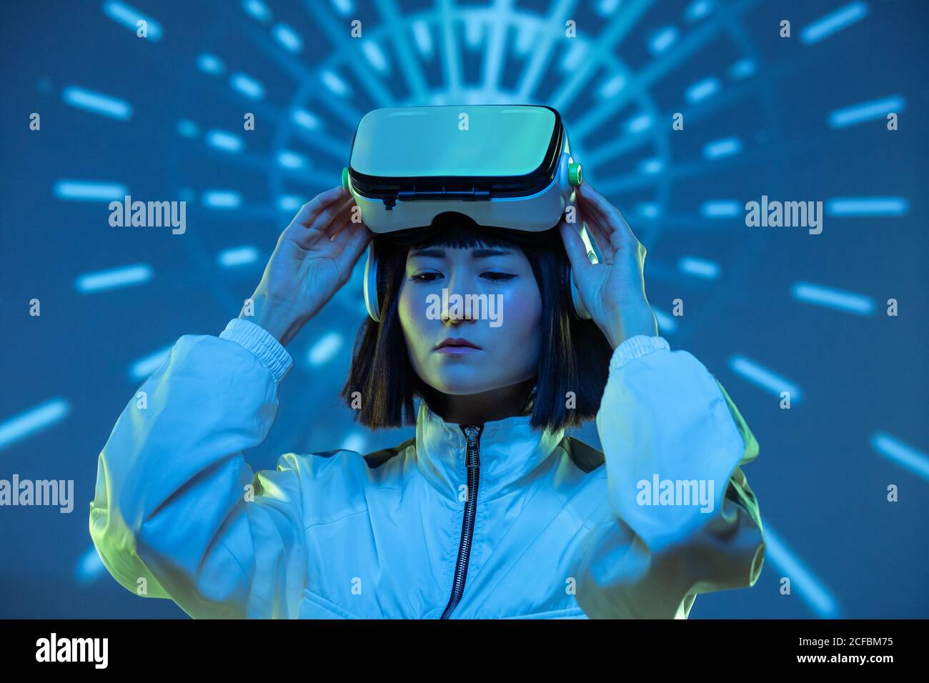 Excited young Woman having virtual reality experience in neon light ...