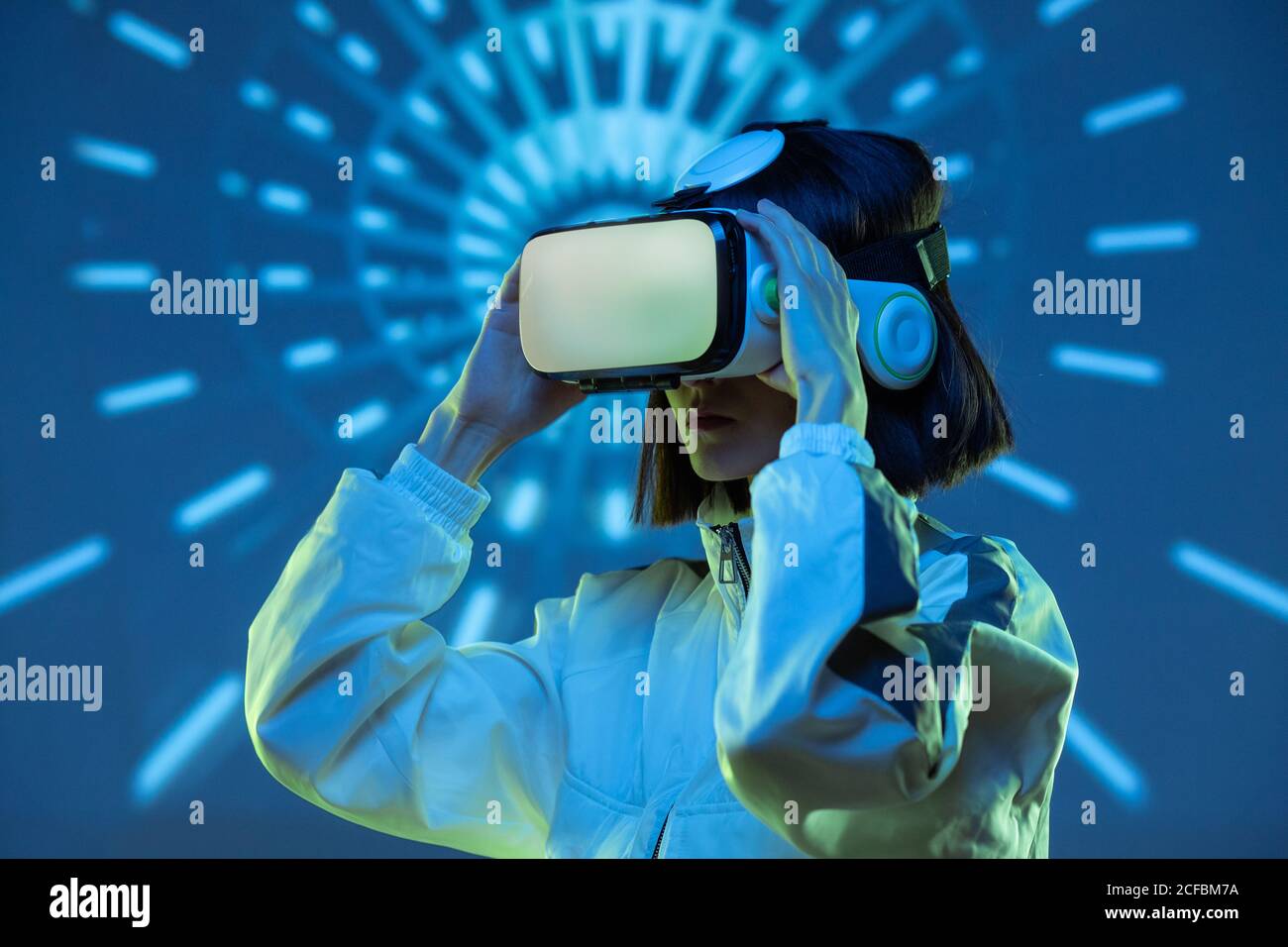 Excited young Woman having virtual reality experience in neon light ...