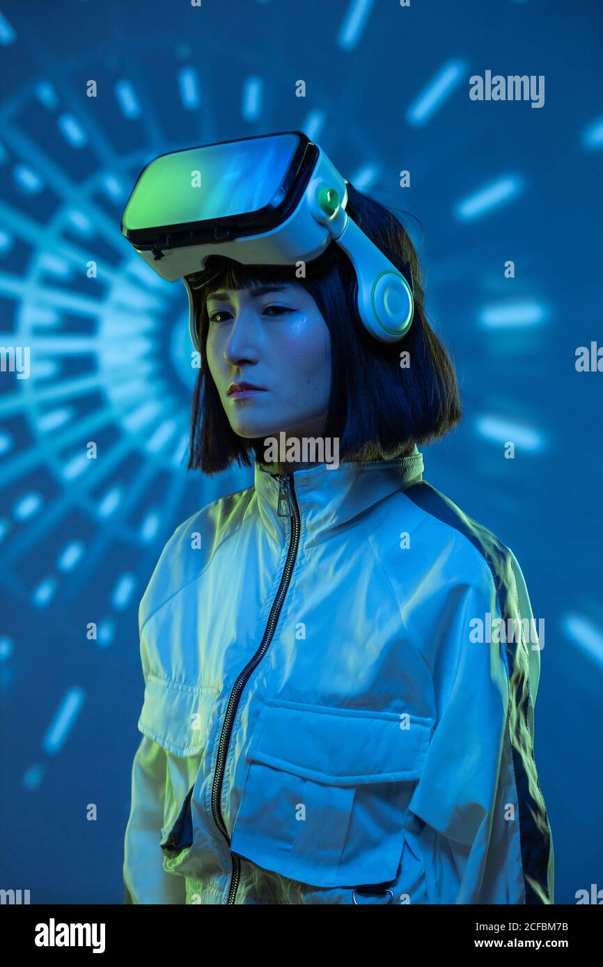 Excited young Woman having virtual reality experience in neon light ...