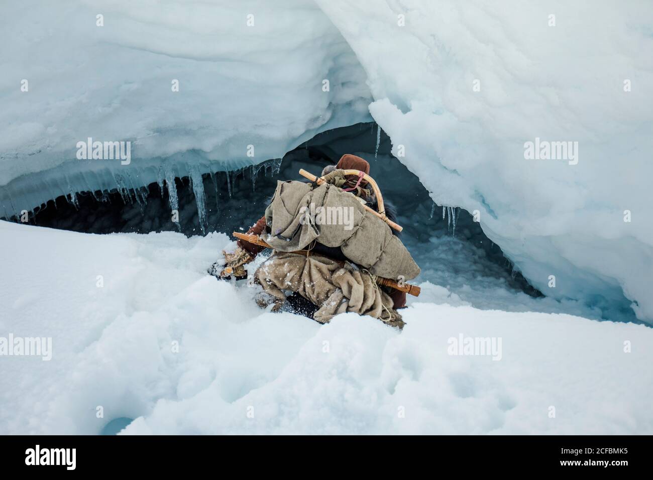 Aboriginal explorer slides down into a ice cave entrance Stock Photo ...