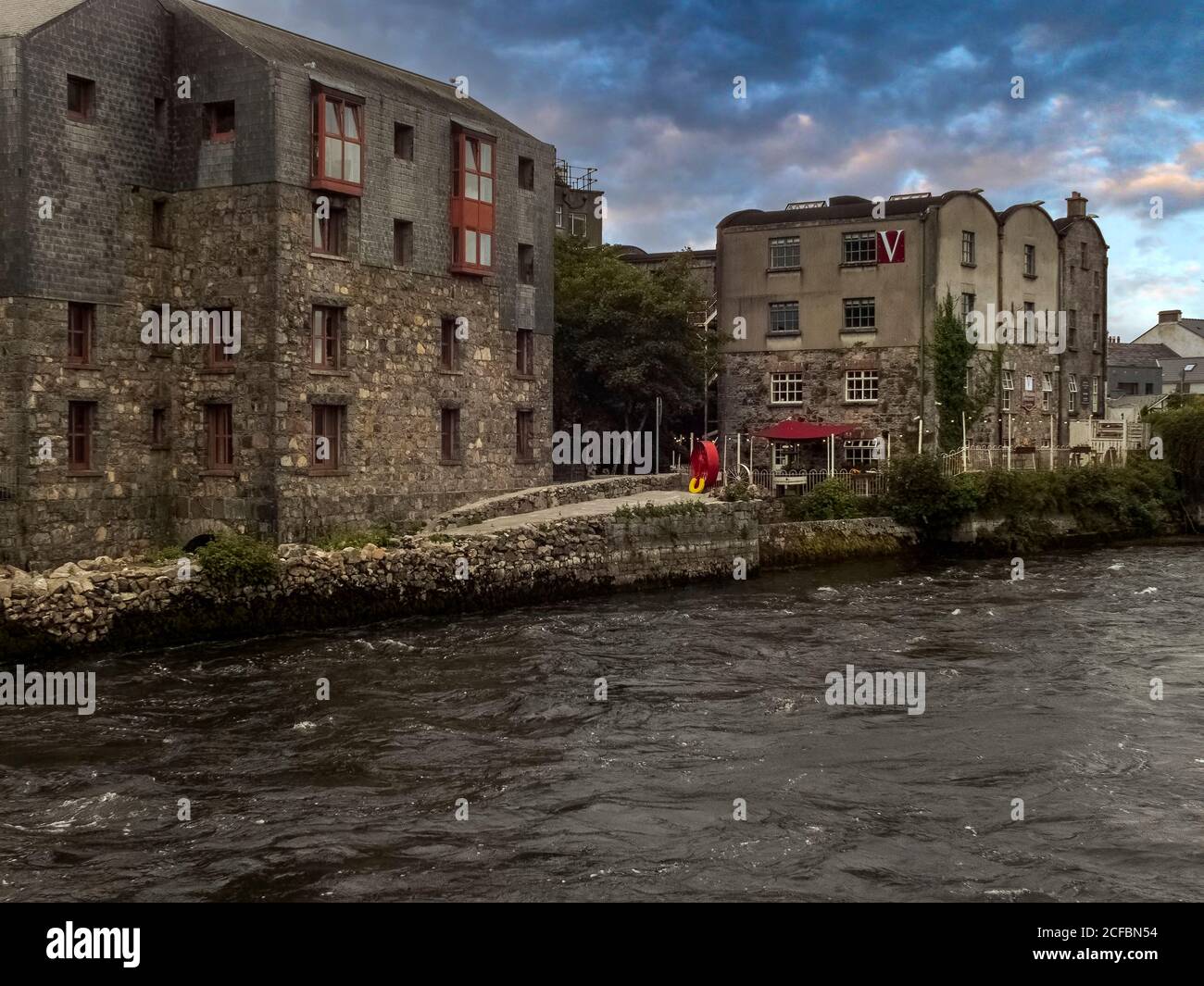 Old stone buildings on the bank of Corrib River in the town of Galway ...