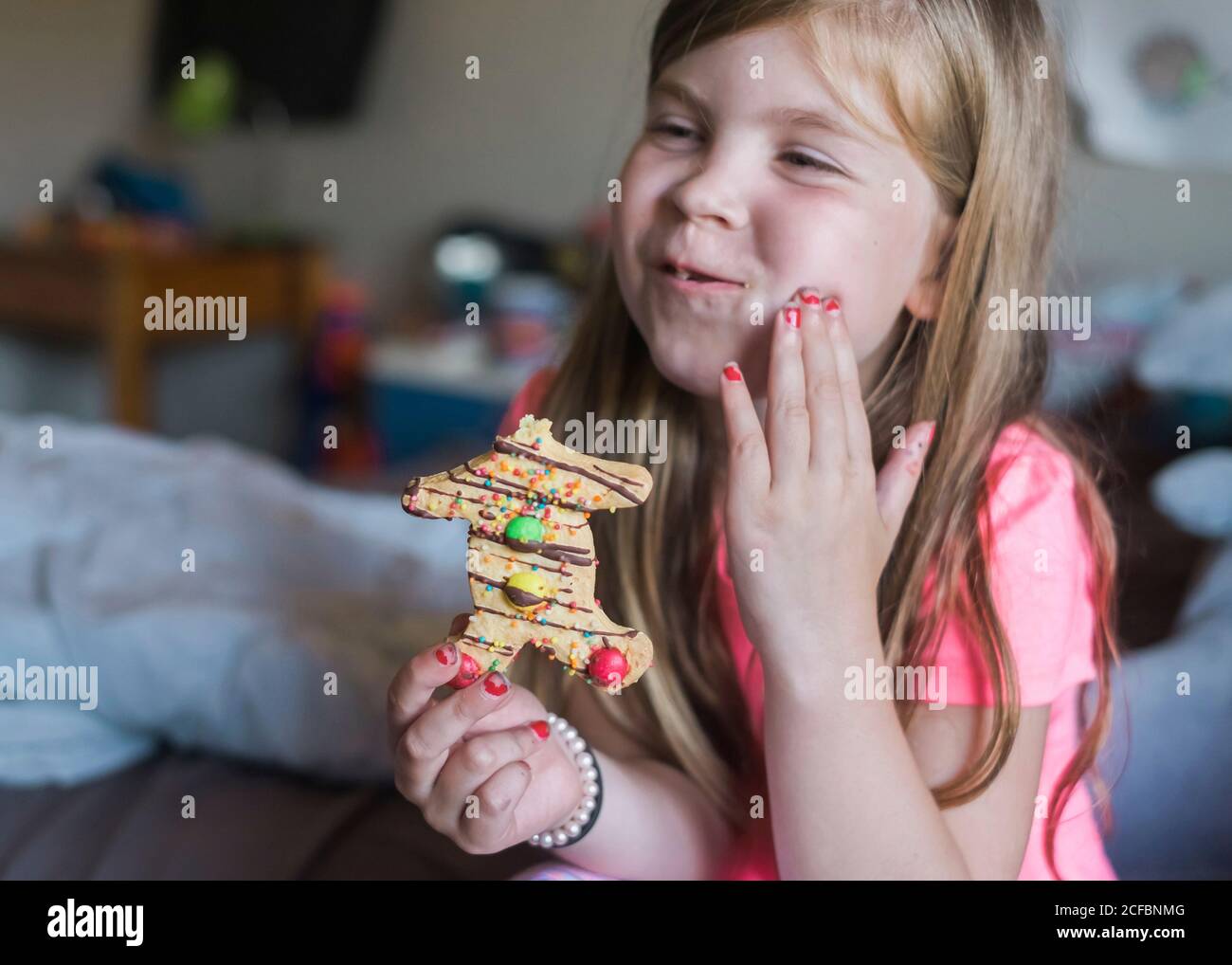 Young girl eating a gingerbread man in her bedroom Stock Photo - Alamy