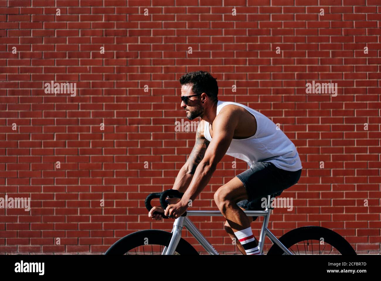 Modern male cyclist in sportswear and sunglasses riding a bicycle near ...