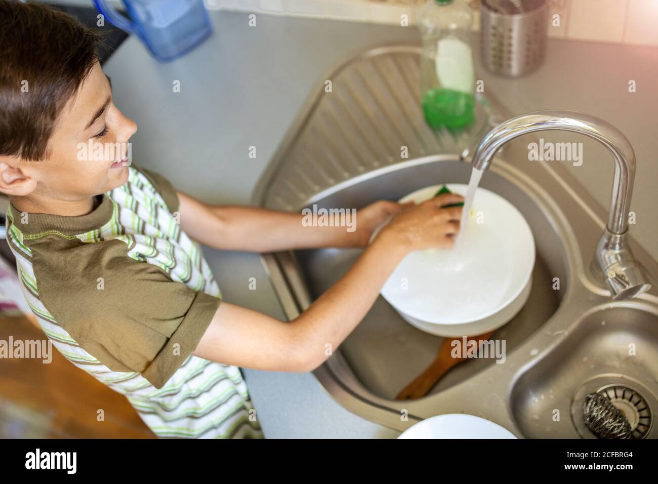 Little boy washing the dishes in the kitchen sink Stock Photo - Alamy