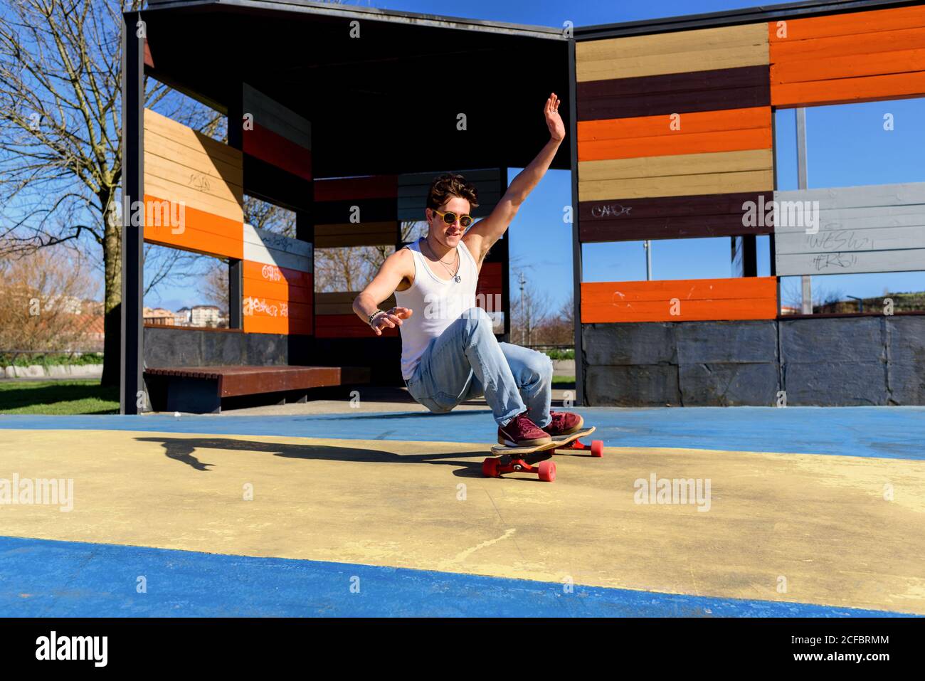 Young handsome male with raised arms falling from skateboard while ...