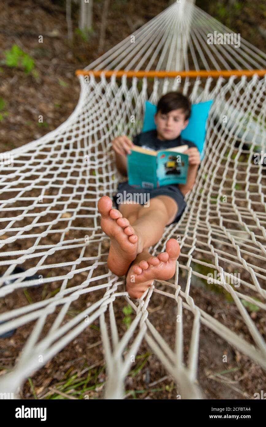 Boy laying in hammock reading hi-res stock photography and images - Alamy