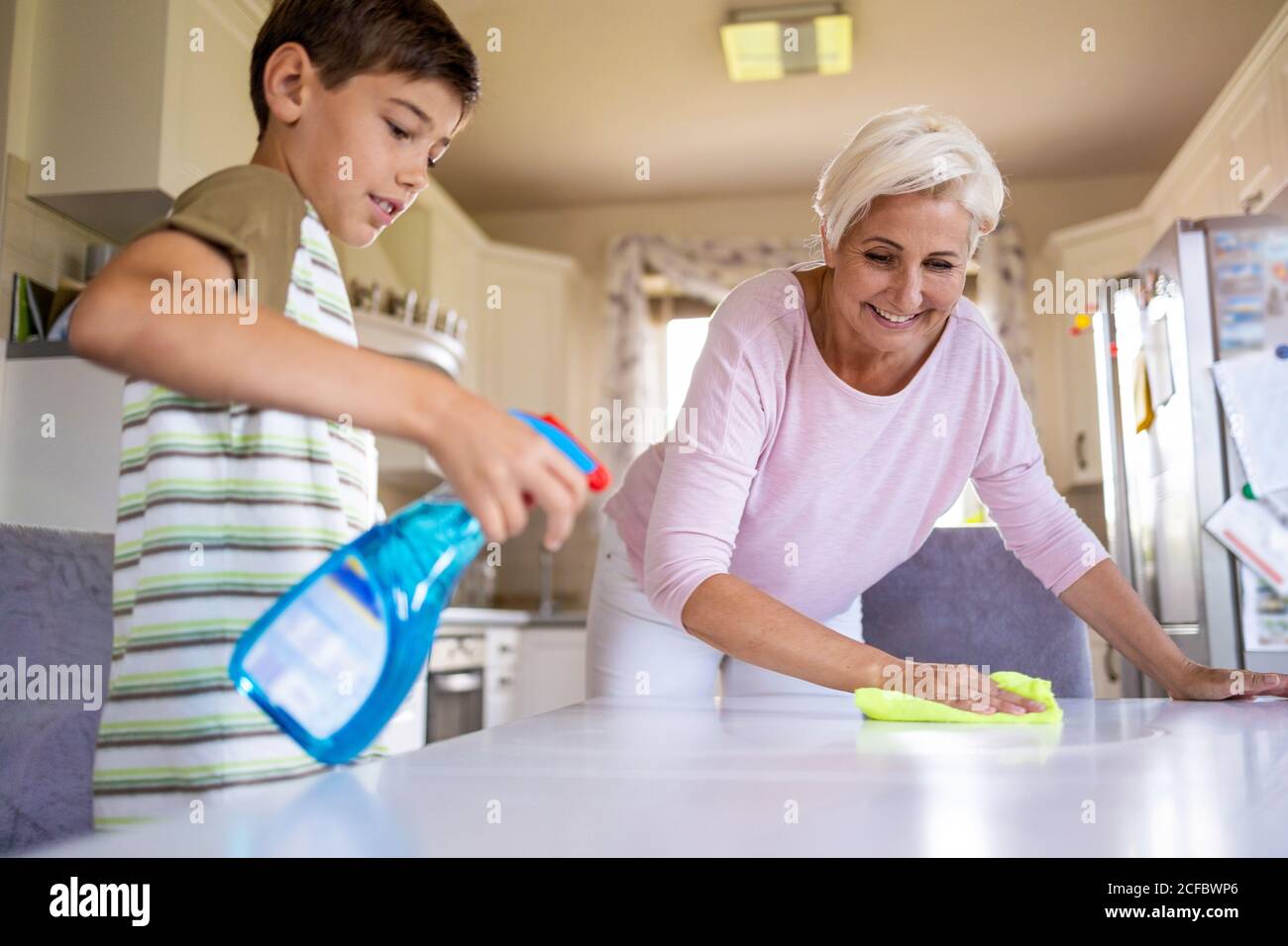 Mother and her son cleaning kitchen surface together at home Stock ...