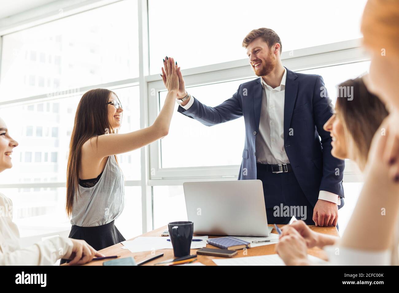 High-five! Two cheerful young business people giving high-five while ...