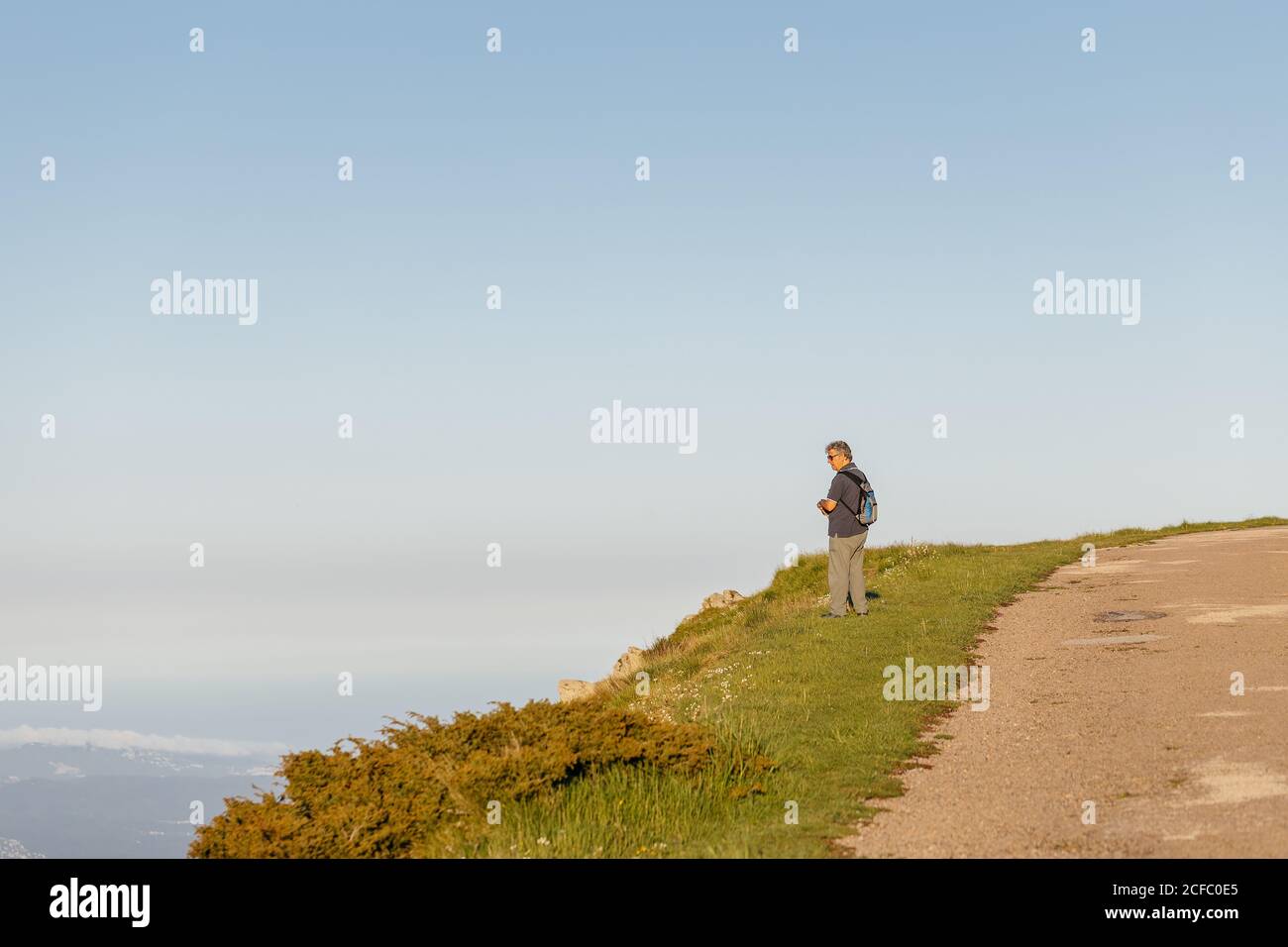 Side view of a senior man with back pack hiking through the mountain ...