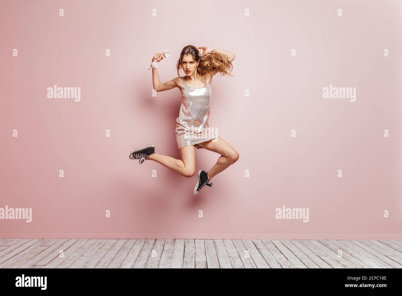 young girl jumping with a phone on pink background Stock Photo - Alamy