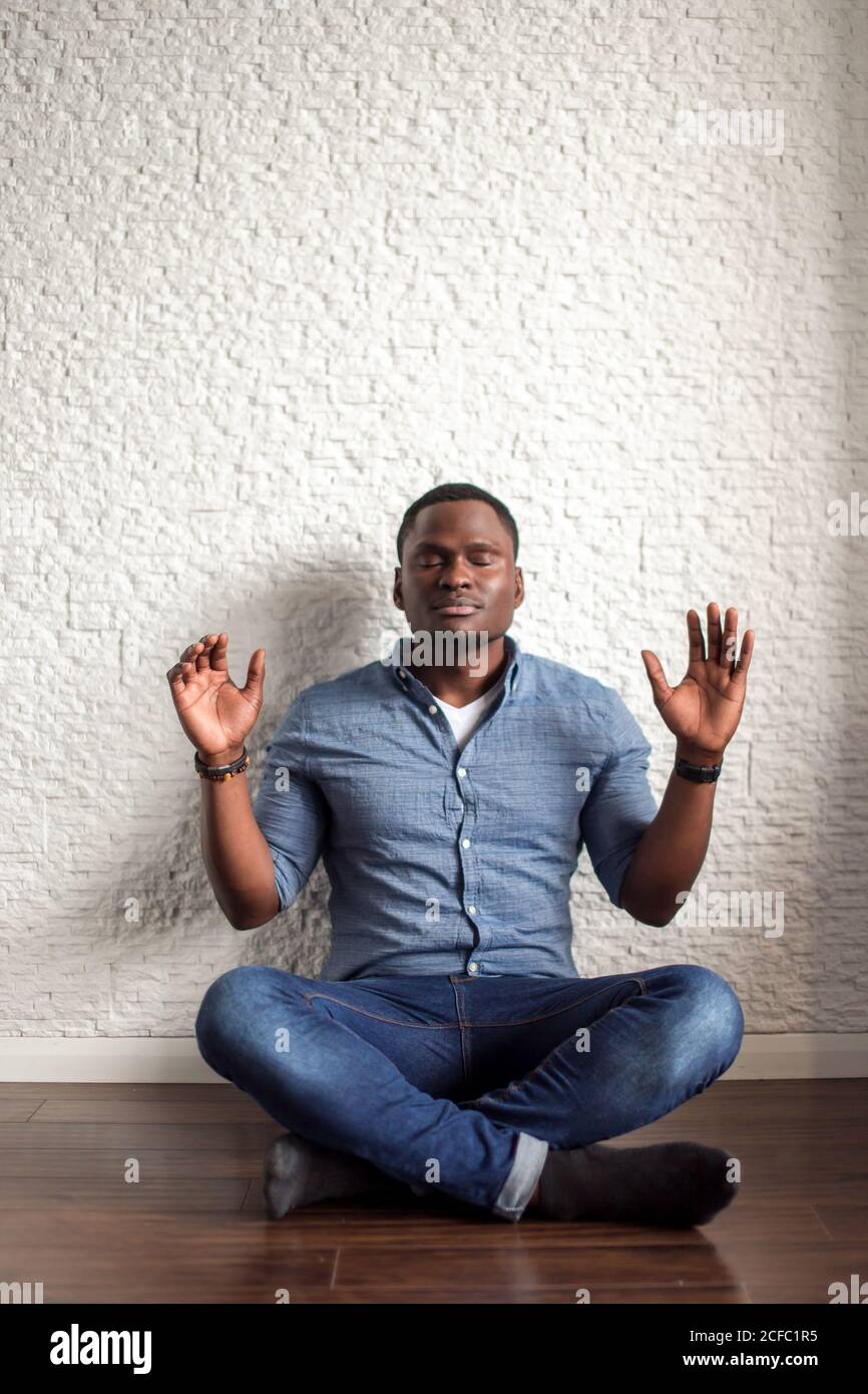 Relaxed handsome african young man sitting and meditating on office ...