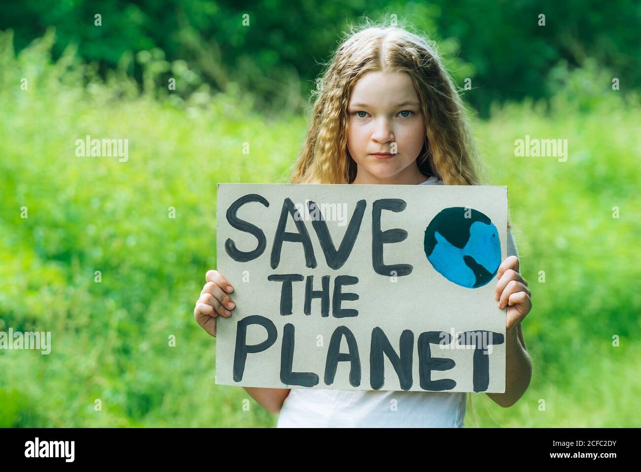 caucasian blonde girl activist with save the planet poster in park ...