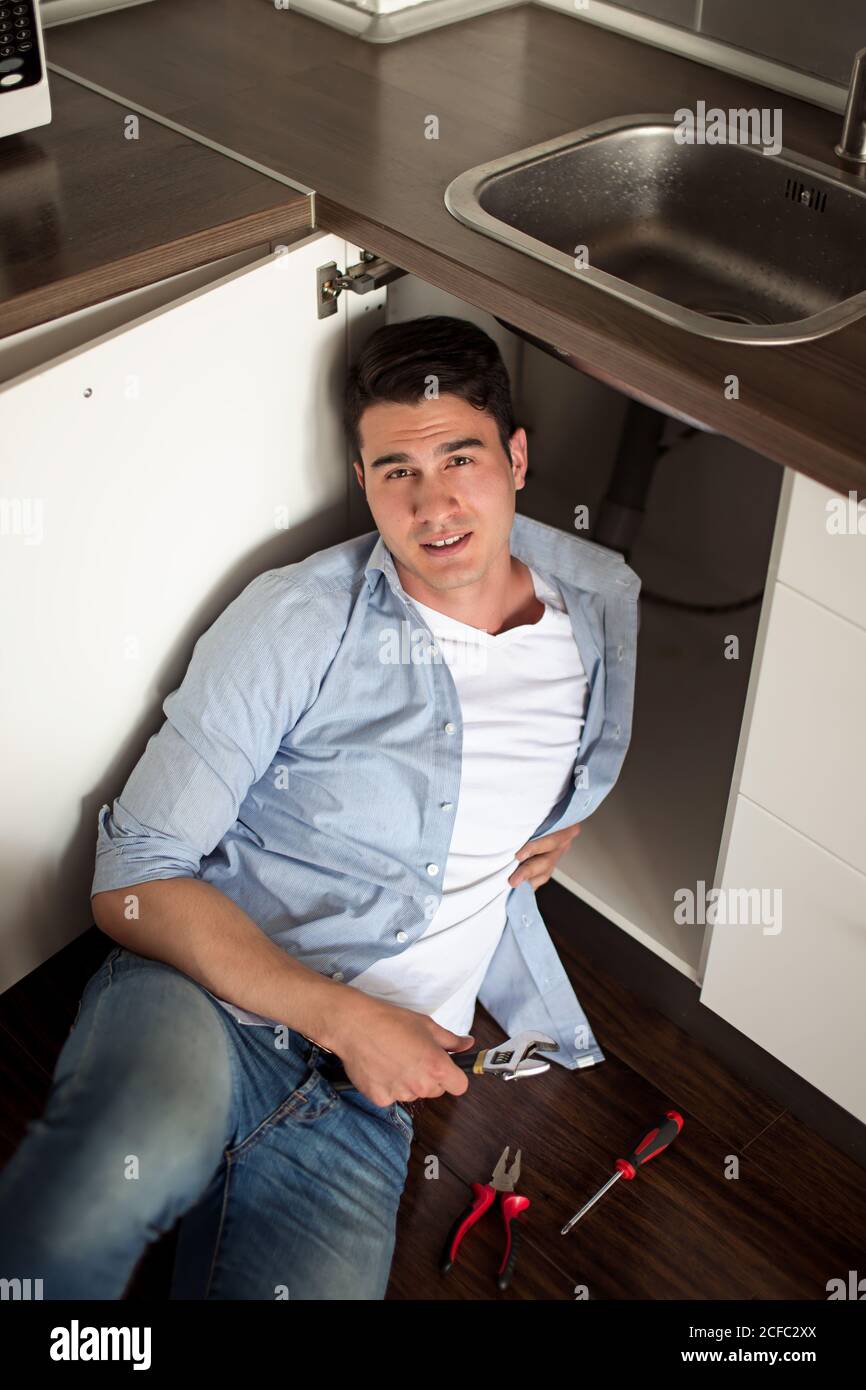 Portrait of male plumber fixing a sink in kitchen Stock Photo - Alamy