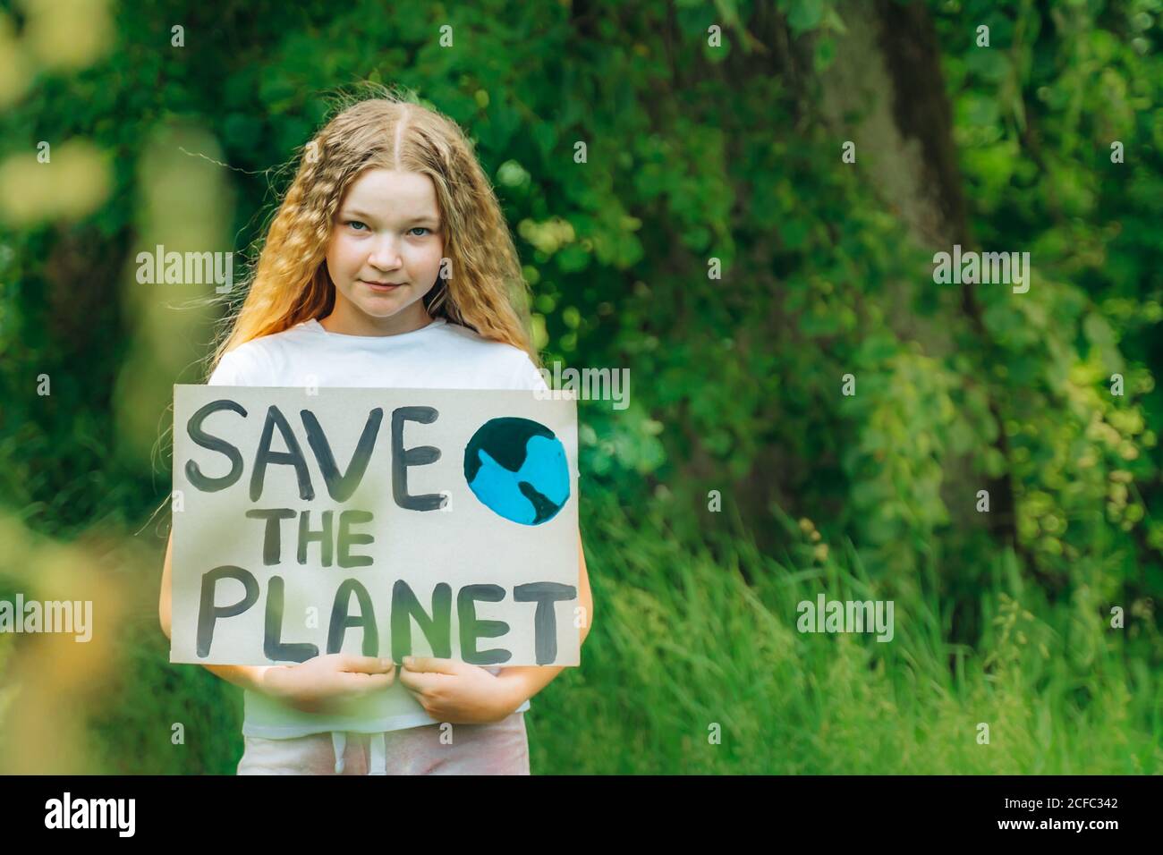 child girl activist with save the planet poster in forest park. preteen ...