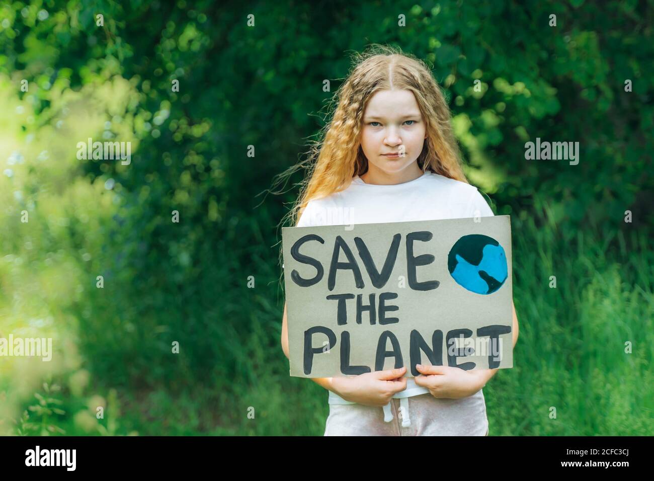 portrait of young girl standing with Save the planet Poster on school ...