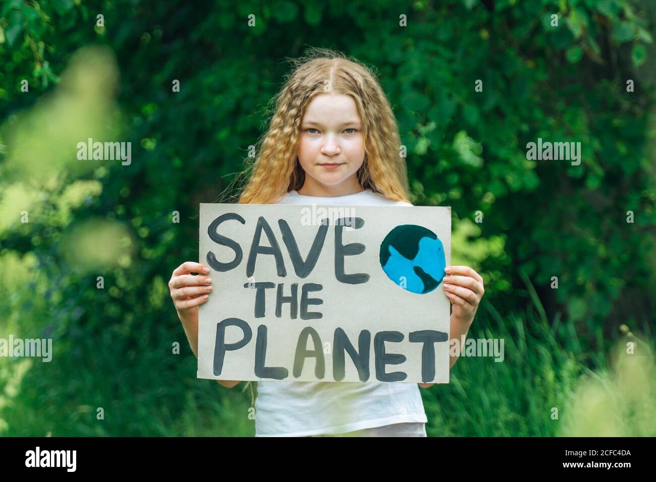 teenager looking to camera with save planet ecology poster in hands ...