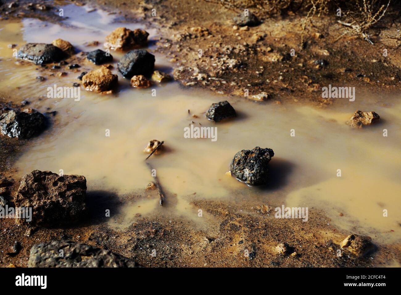 From above swamp with turbid muddy water brown soil and black rocks ...