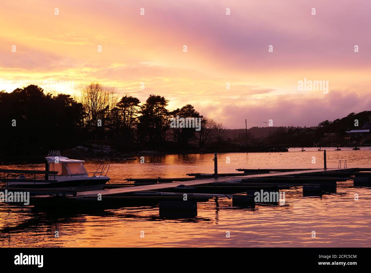 Still waterfront with wharf and boat over pastel purple sky and dark ...