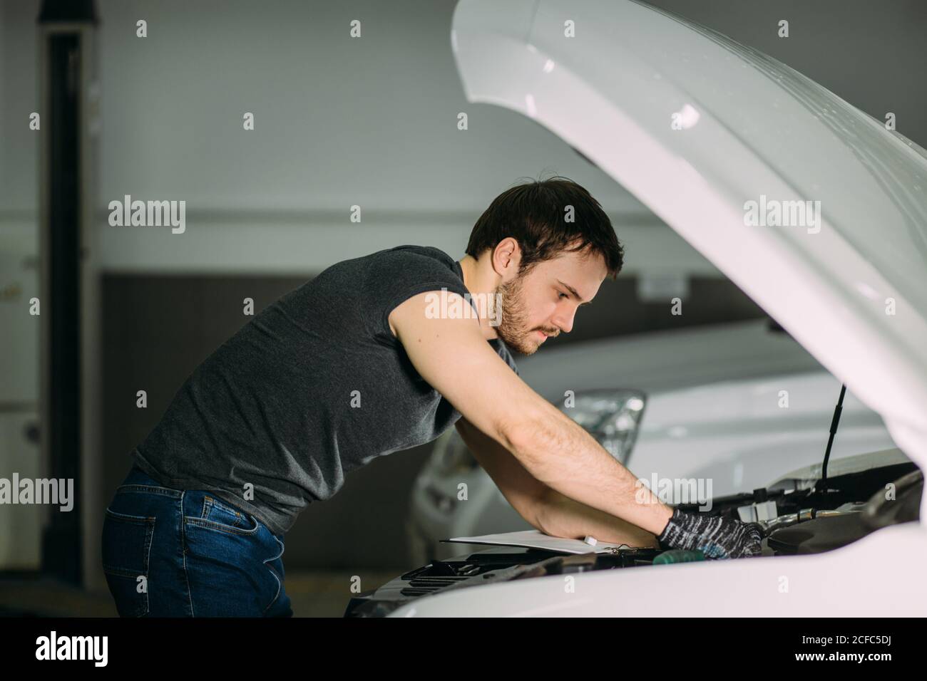 mechanic working in car hood in garage Stock Photo - Alamy