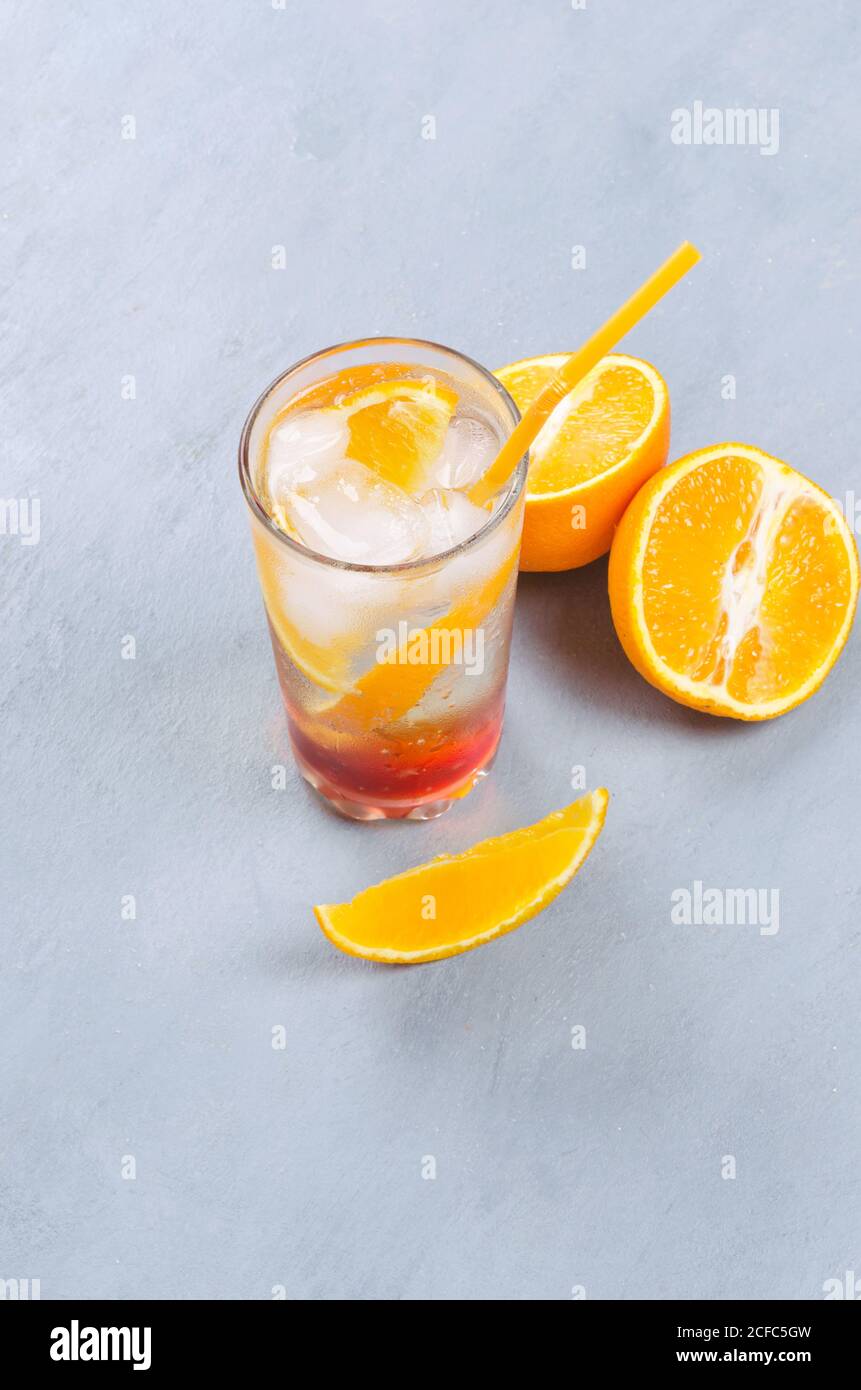 Orange alcohol cocktail with orange fruit slice on pink and gray ...