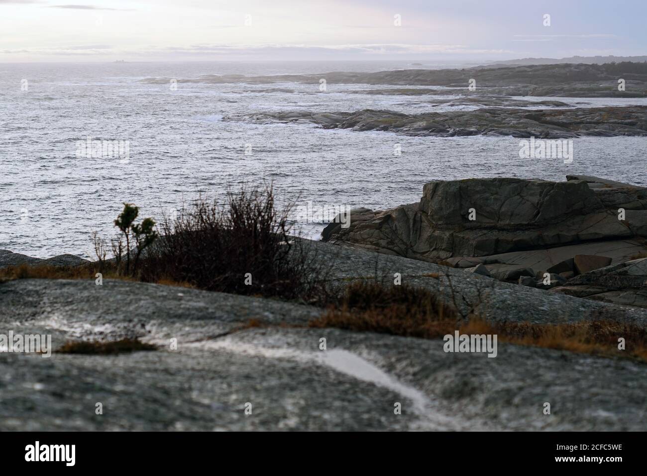 Smooth boulders on empty coast with sea waves under dark evening sky in ...