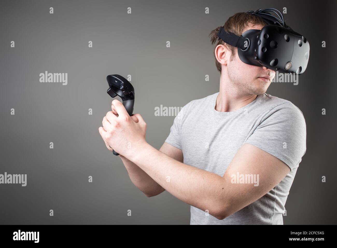 Man wearing virtual reality goggles and keep the joystick as a weapon ...