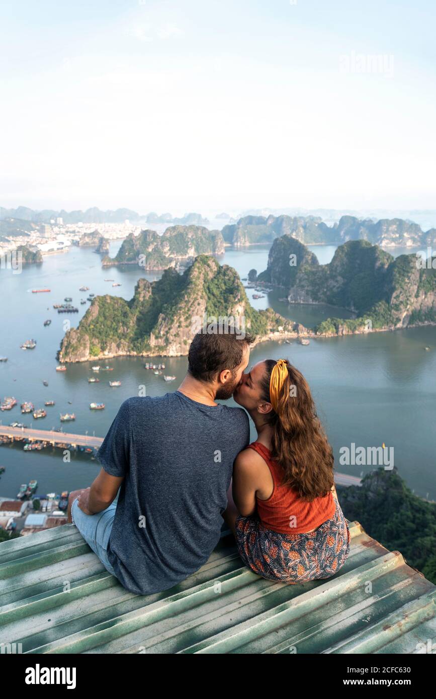 From above back view of loving couple sitting on metal roof and ...